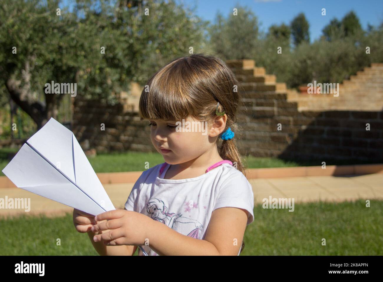 Picture of an adorable little girl playing a little paper airplane ...