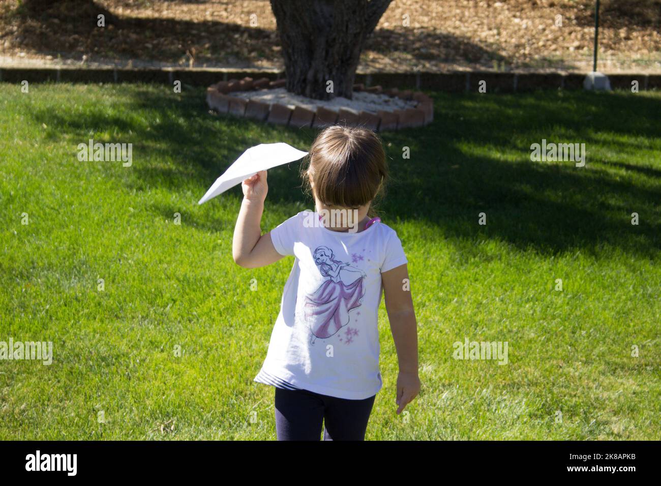 Picture of an adorable little girl playing a little paper airplane ...