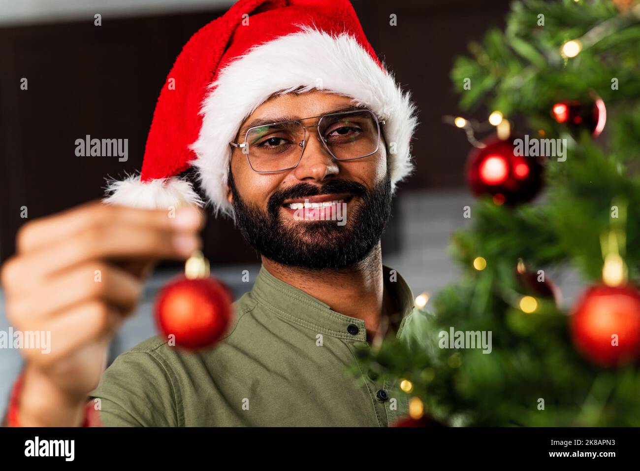 indian man in santa hat decorating Christmas tree with baubles Stock ...