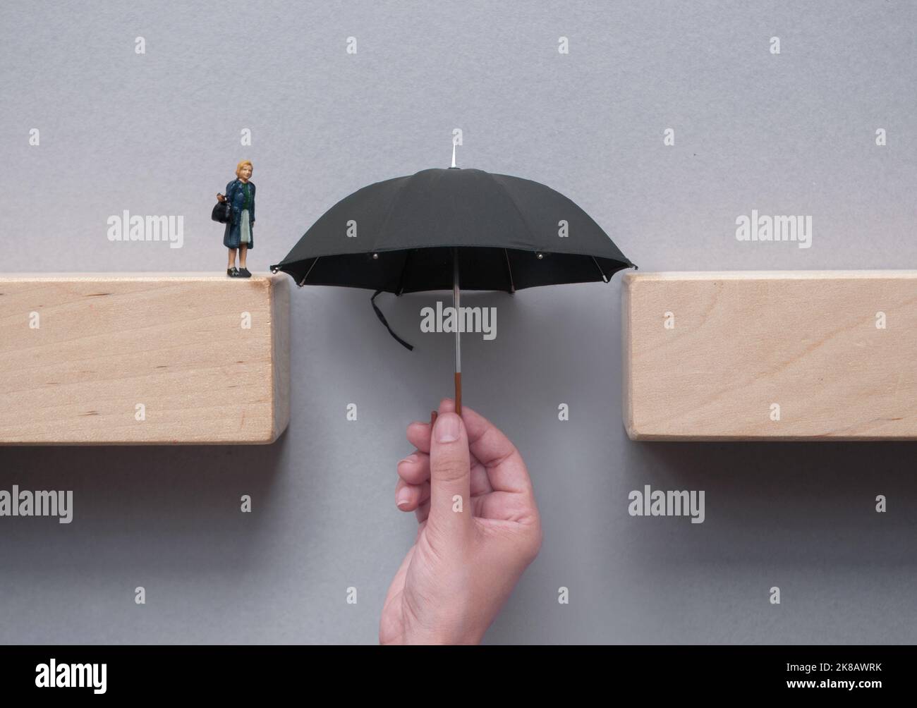 Hand holding umbrella bridging the gap between wooden blocks safe ...