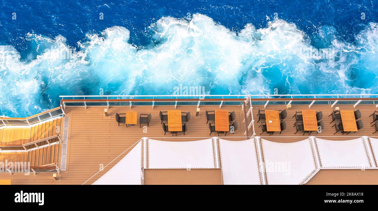 View of tables and chairs on a deck of a cruise ship sailing with the ...