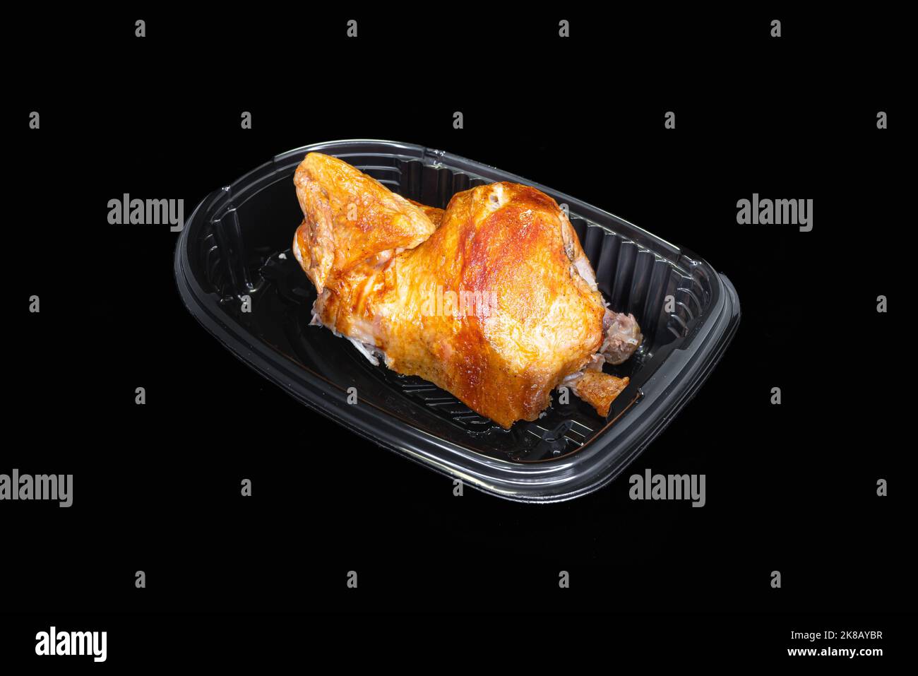 Roasted half chicken in a black package on a black background Stock ...