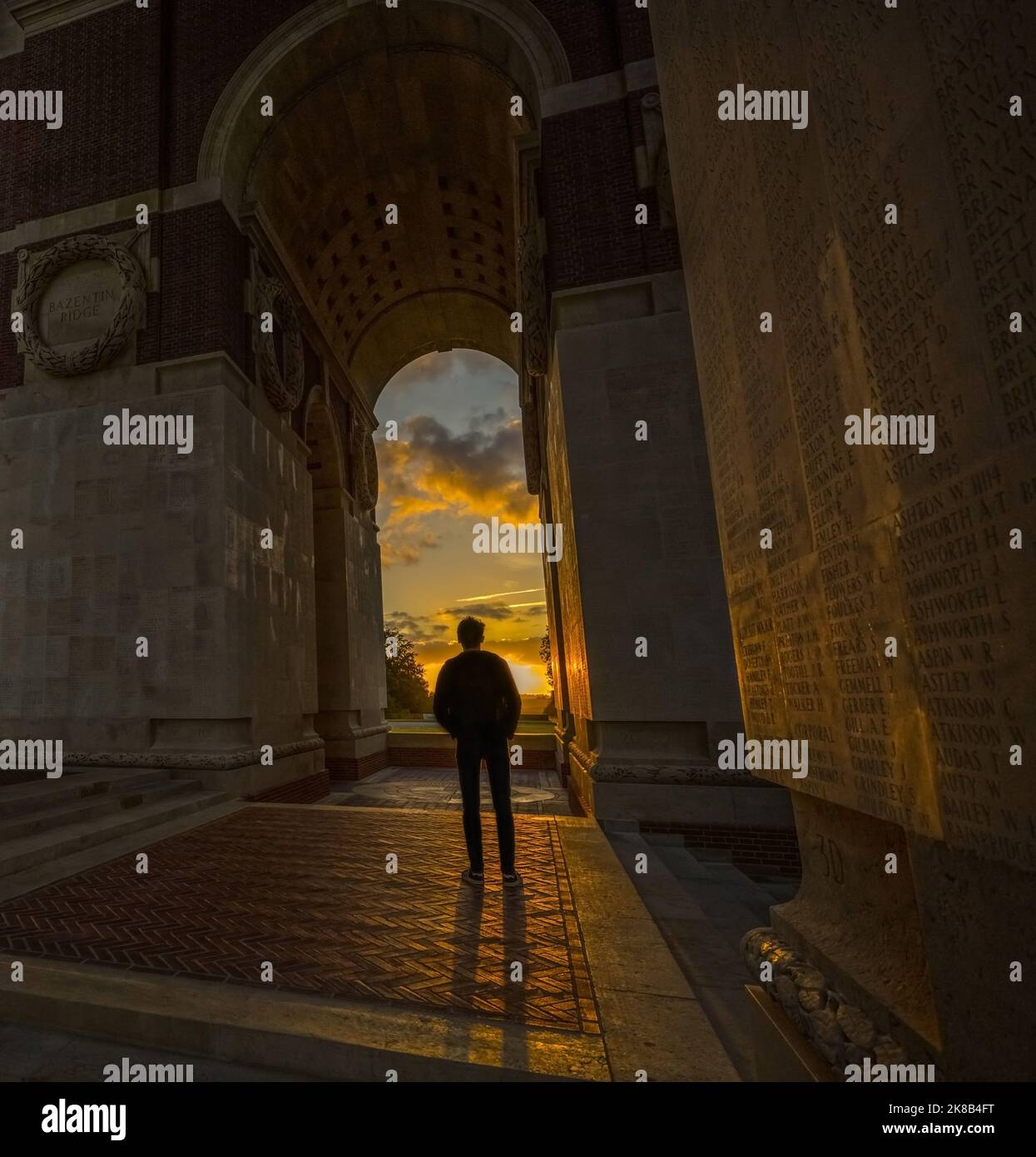 A young man looks towards the sunrise on a new day at Thiepval Memorial ...