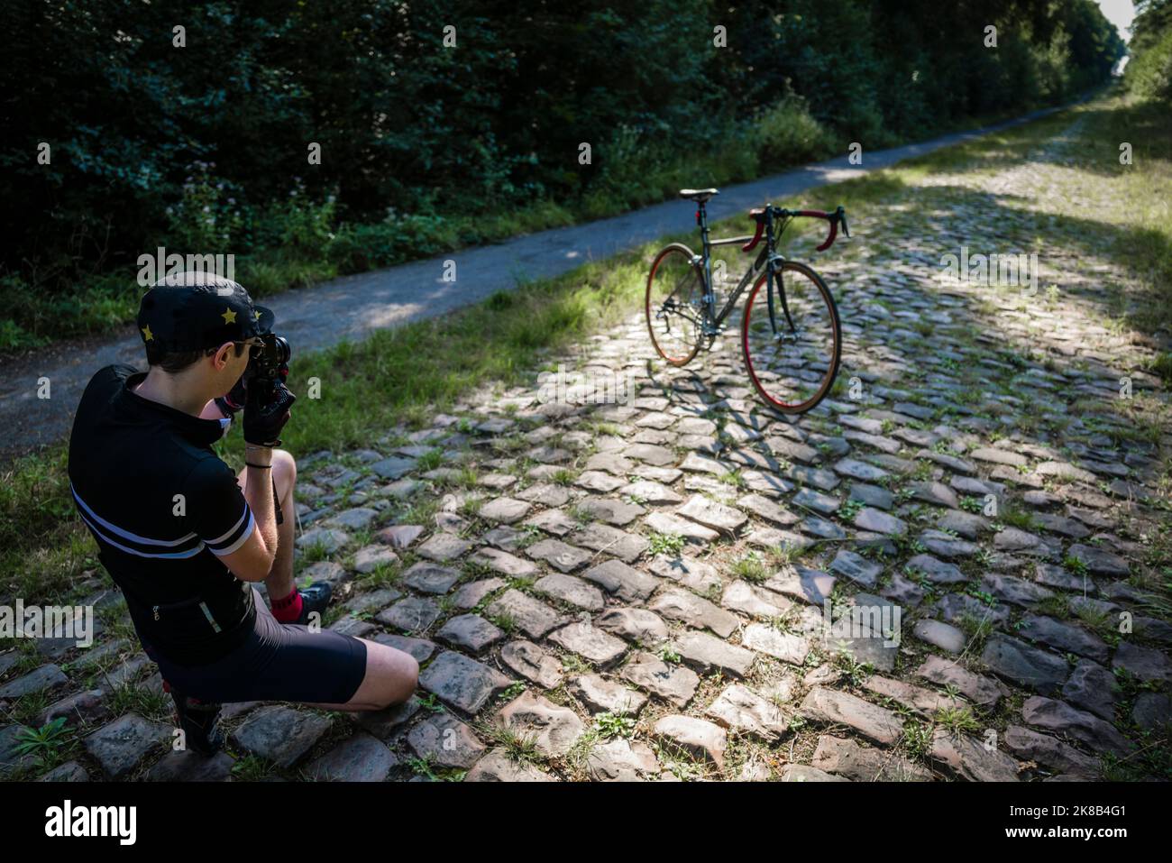 A photographer on a shoot with titanium road bike and the cobbles of ...