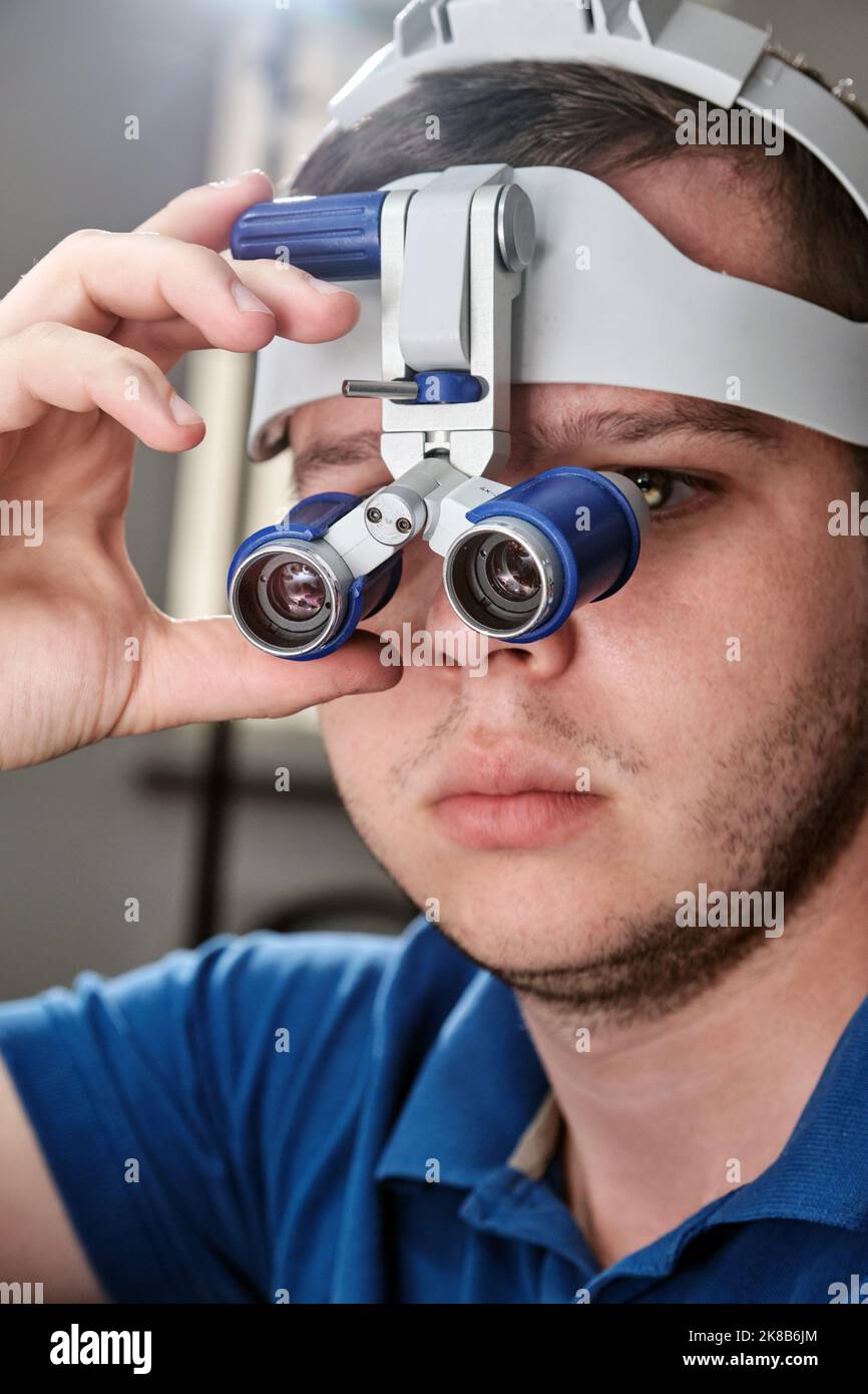 Dentist with binocular magnifying glasses working in dental clinic ...