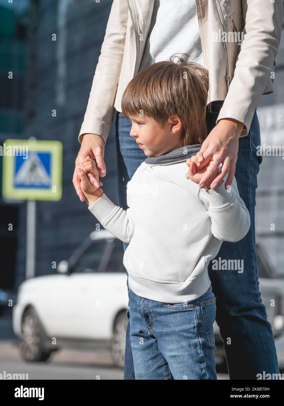 Mother and son stand on street in sunlight. Woman and kid in modern ...