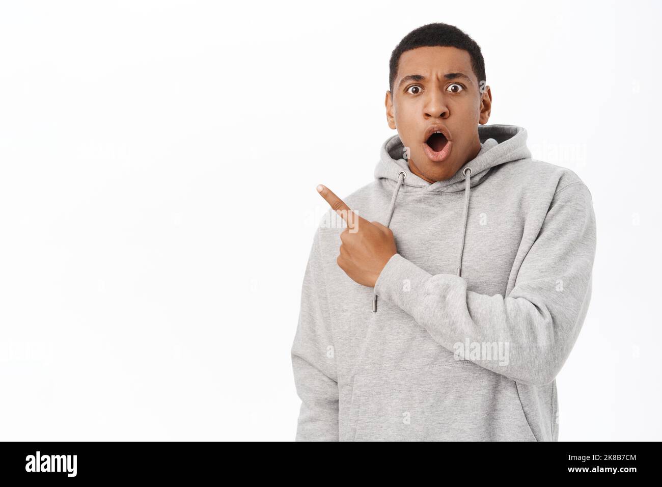 Image of shocked african american man pointing finger left, looking ...