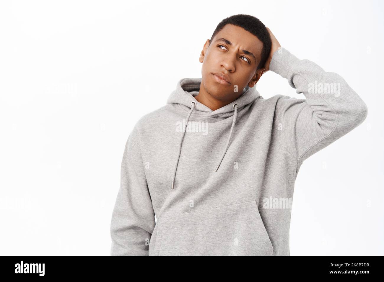 Portrait of Black man scratches his head and looks puzzled, thinks with ...