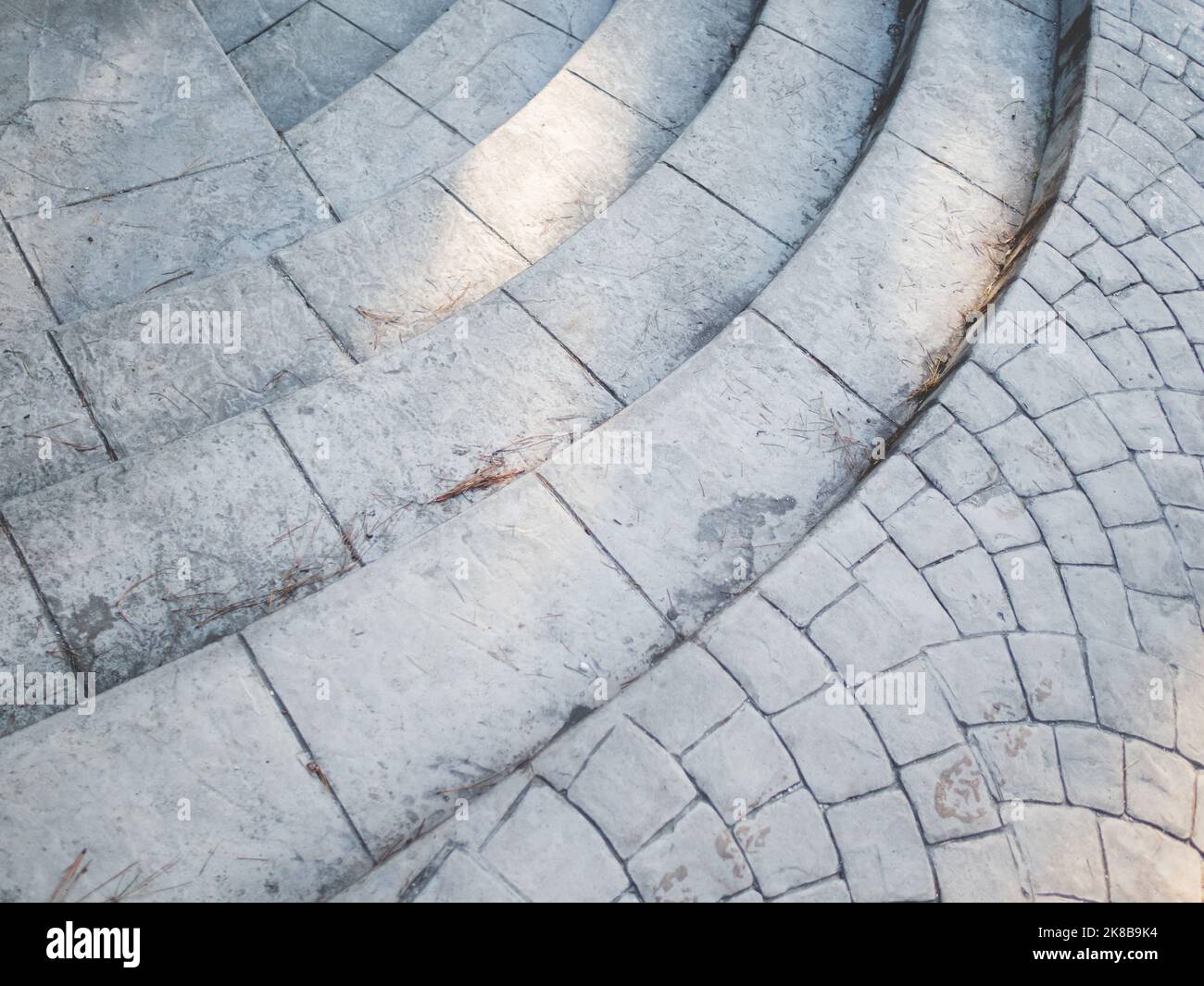 Exterior of grey tiled staircase. Sunlight and shadow on stone curved ...