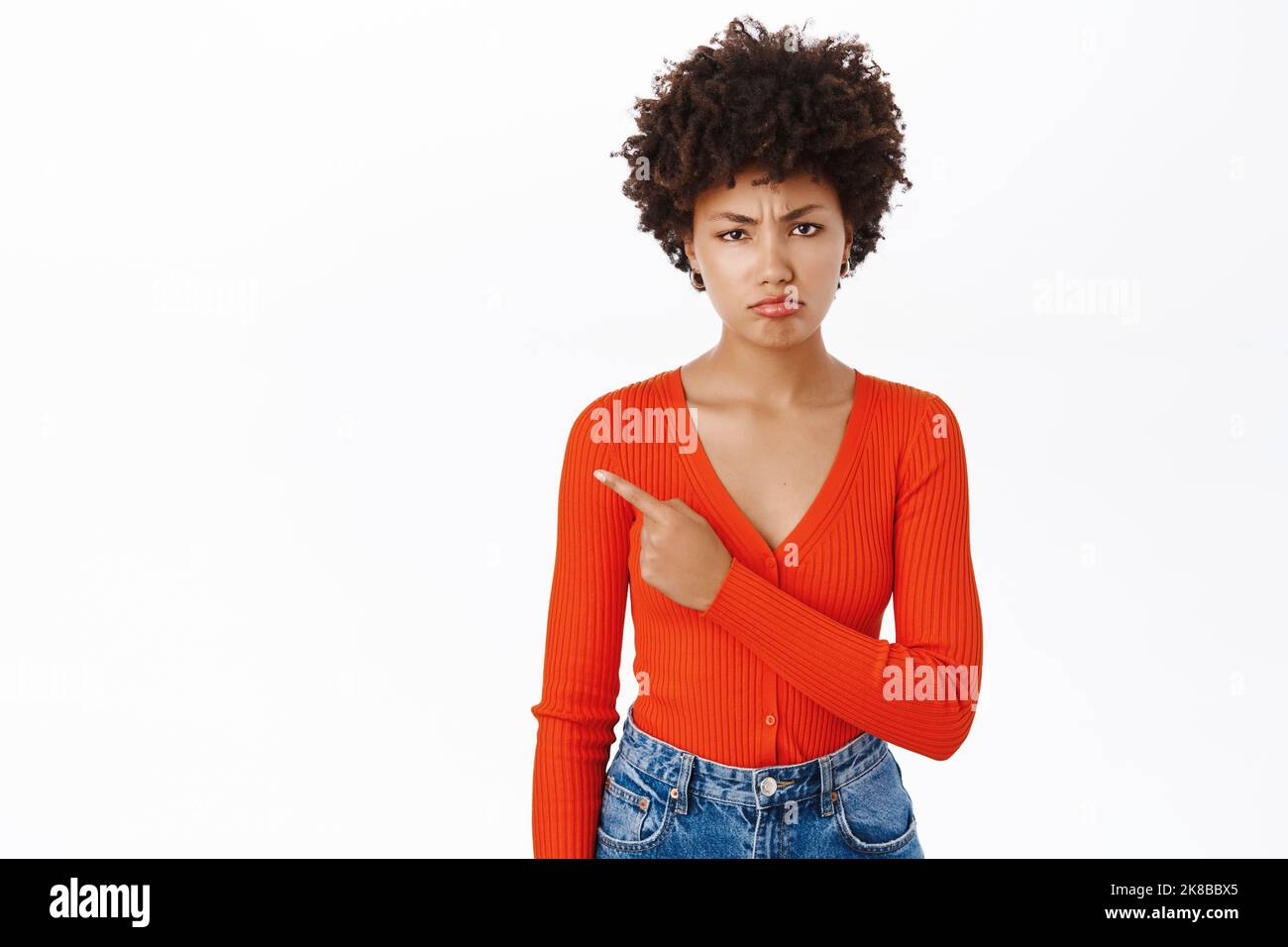 Beautiful girl with upset, disappointed face, pointing finger left ...