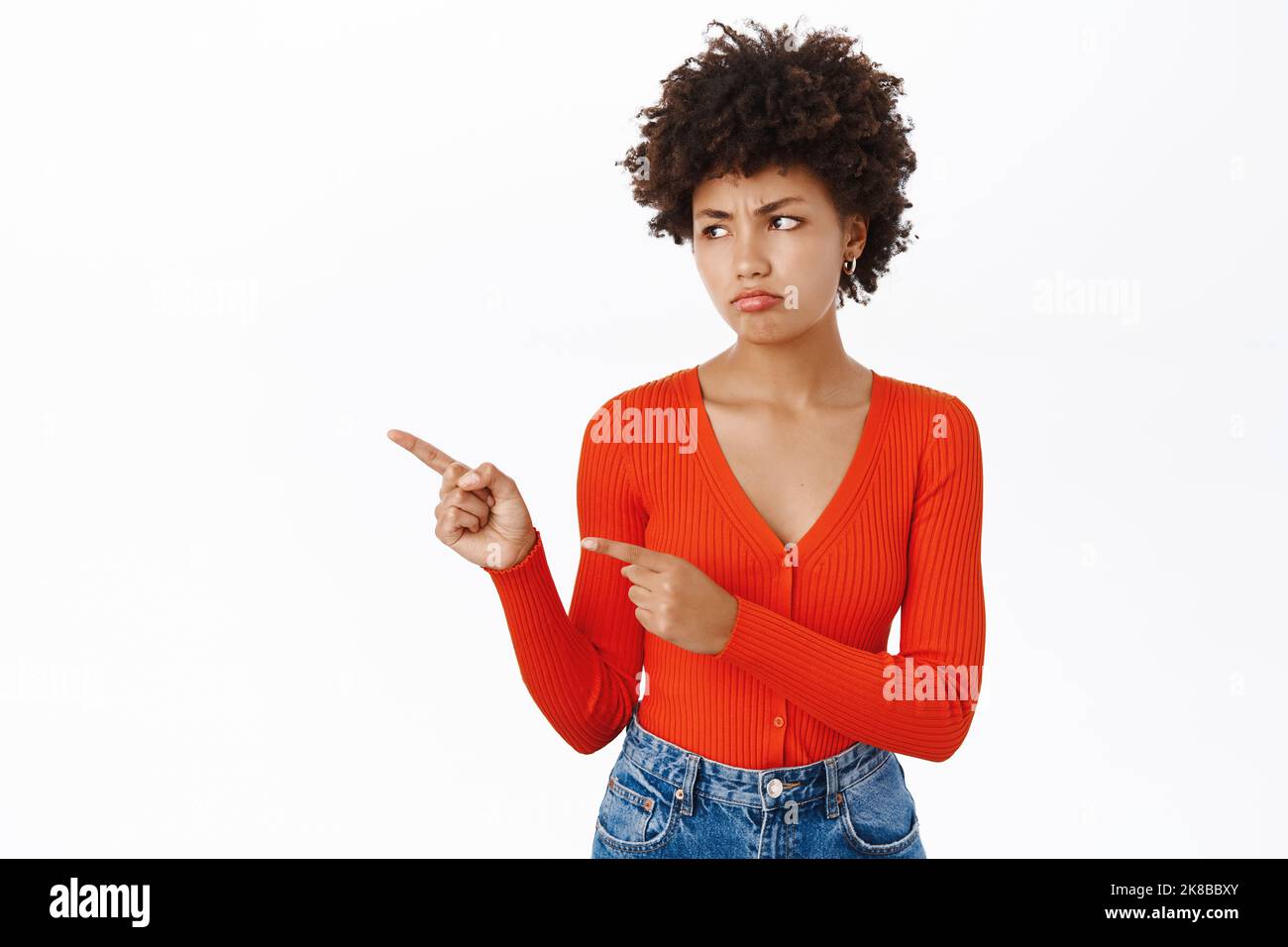 Beautiful girl with upset, disappointed face, pointing finger left ...