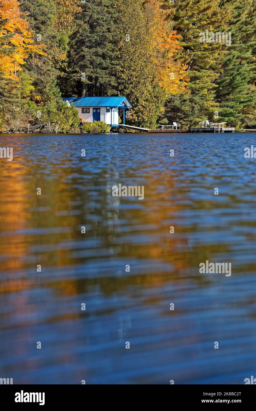 Fall colors forest and a small cabin on the shore of a lake reflecting ...