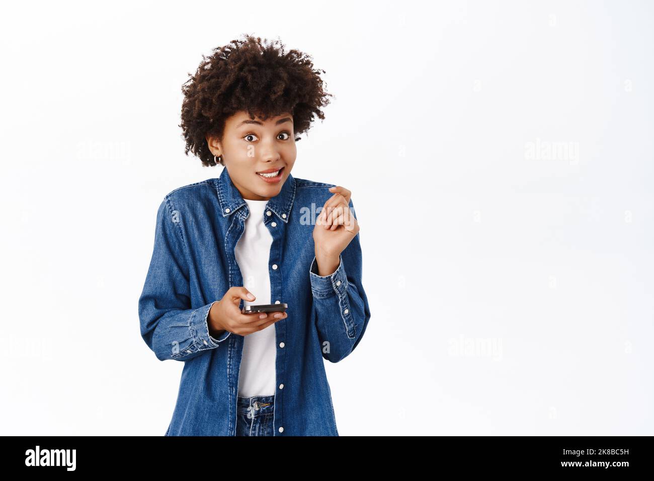 Oops. Young awkward woman uses mobile phone, makes guilty smile and ...