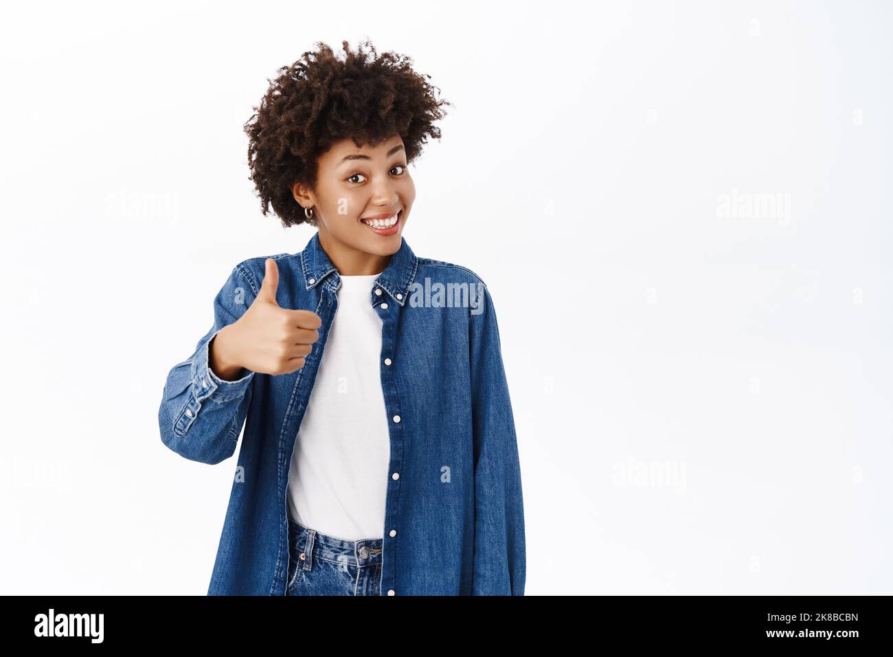 Enthusiastic young beautiful girl shows thumbs up, approves smth ...