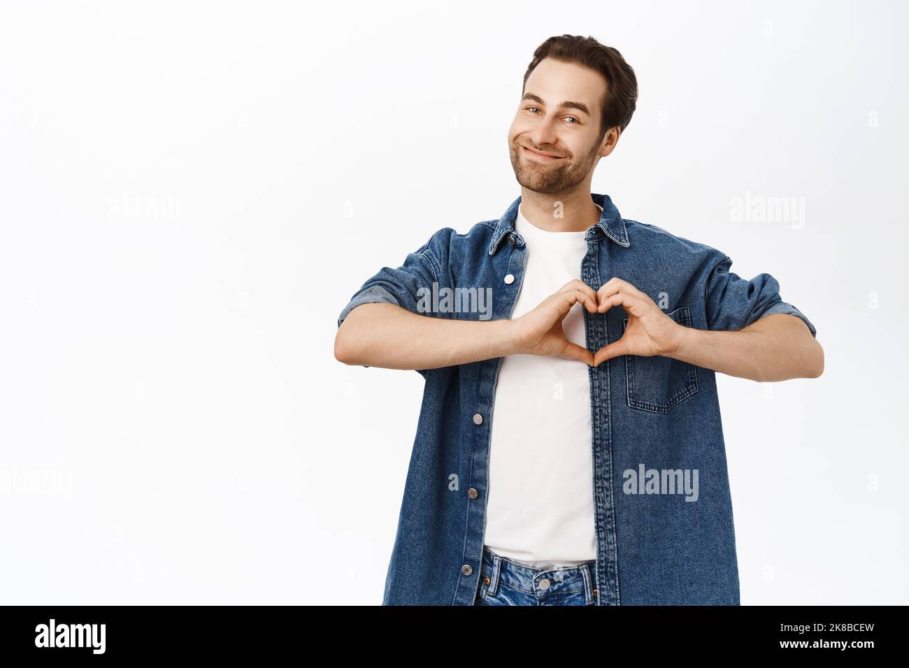 Portrait of handsome man shows heart, love sign with cute smile, adore ...