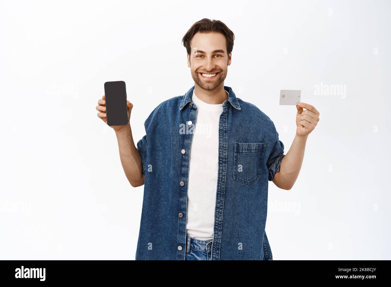Portrait of handsome smiling man shows credit card and mobile phone ...