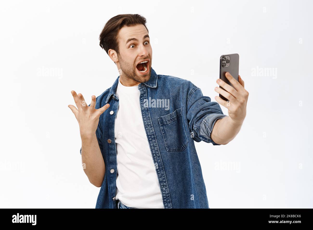 Portrait of guy with mobile phone, wins on smartphone, triumphs ...