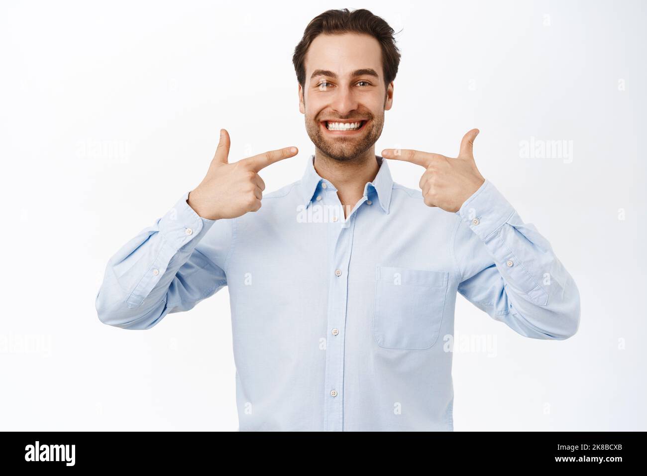 Portrait of smiling handsome businessman pointing at his white perfect ...