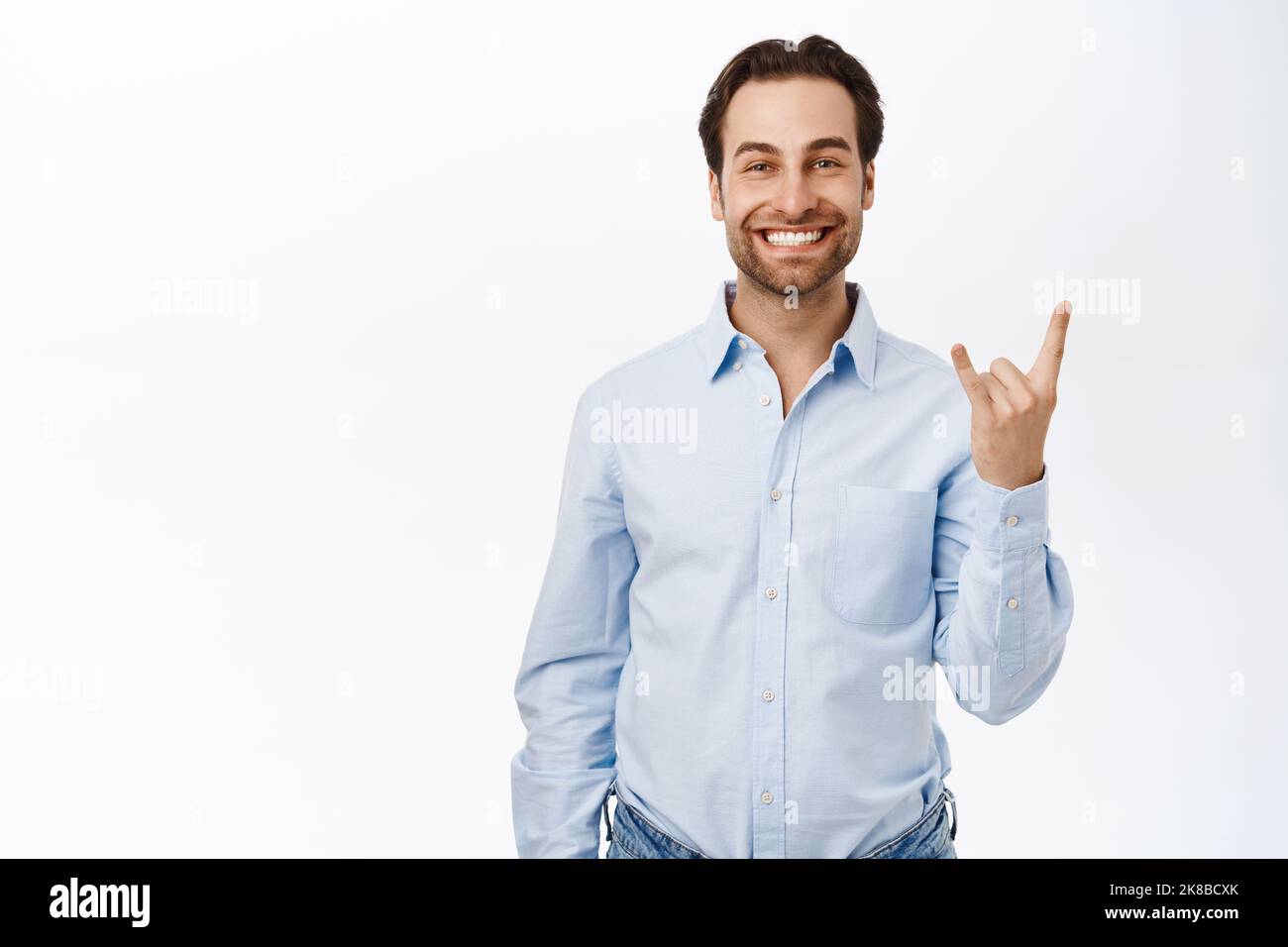 Happy office guy shows rock on, heavy metal horns sign and smiles ...