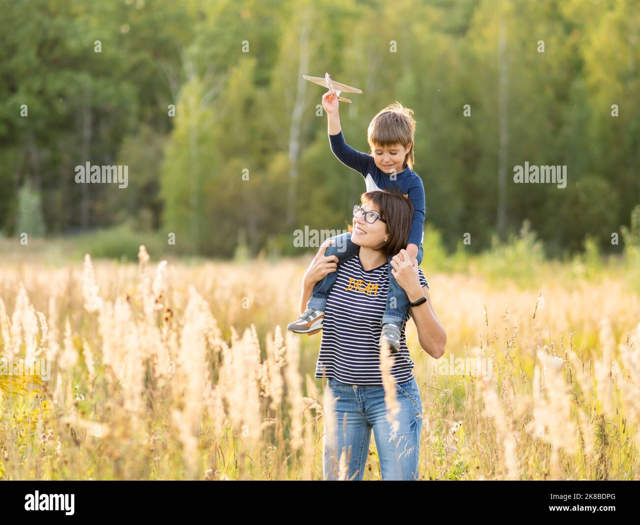 Cute boy and his mother play with toy air plane. Happy kid dreams to be ...