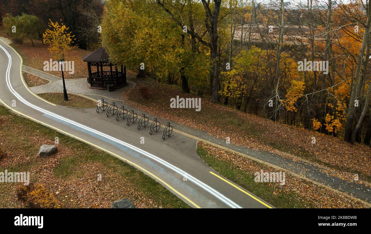 Autumn city park. Trees with colorful leaves. A cycle path winds ...