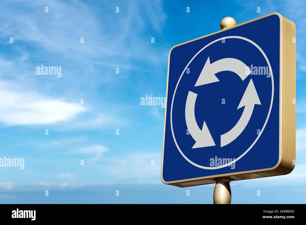 Close-up of a blue and white roundabout road sign against a clear blue ...