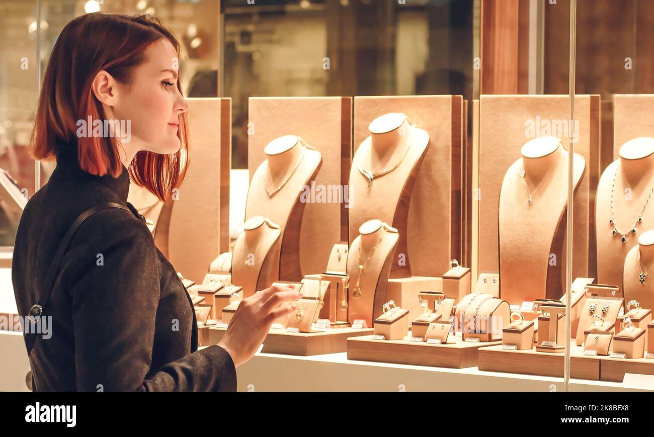 Pretty woman looking at jewelry in store window. Customer near ...