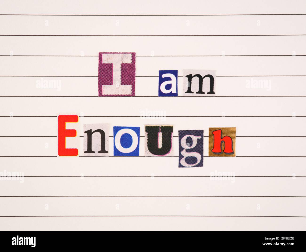 Phrase I am Enough made from letters cutting from magazines on a lined ...