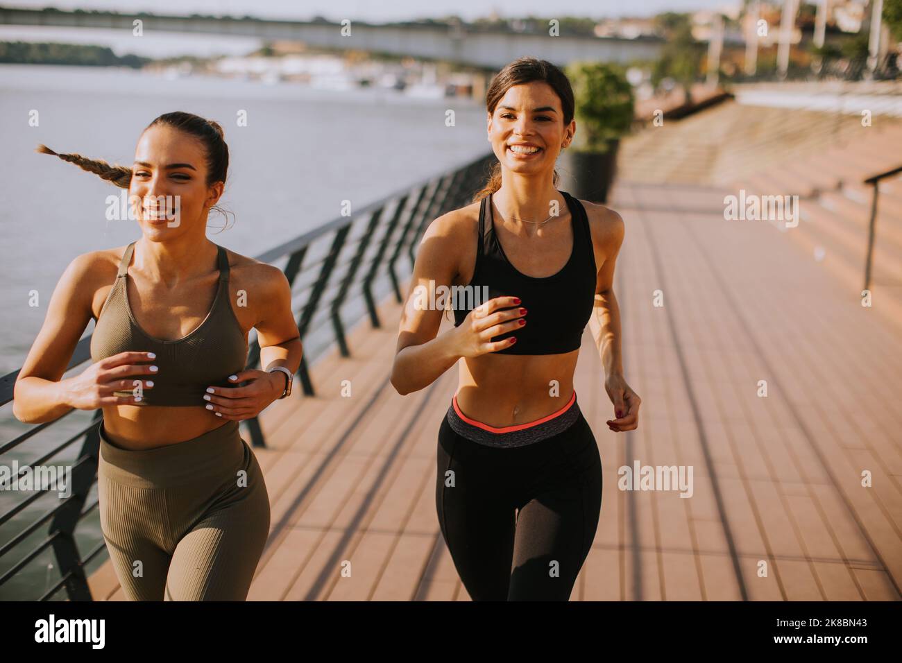 Pretty young woman taking running exercise by the river promenade Stock ...