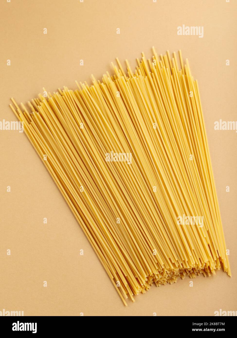Dry spaghetti pasta on a beige background. Yellow italian pasta close ...