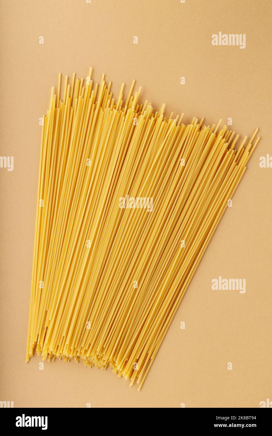 Dry spaghetti pasta on a beige background. Yellow italian pasta close ...