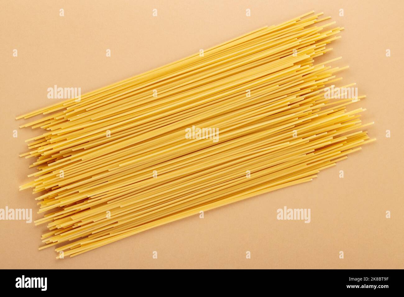 Dry spaghetti pasta on a beige background. Yellow italian pasta close ...