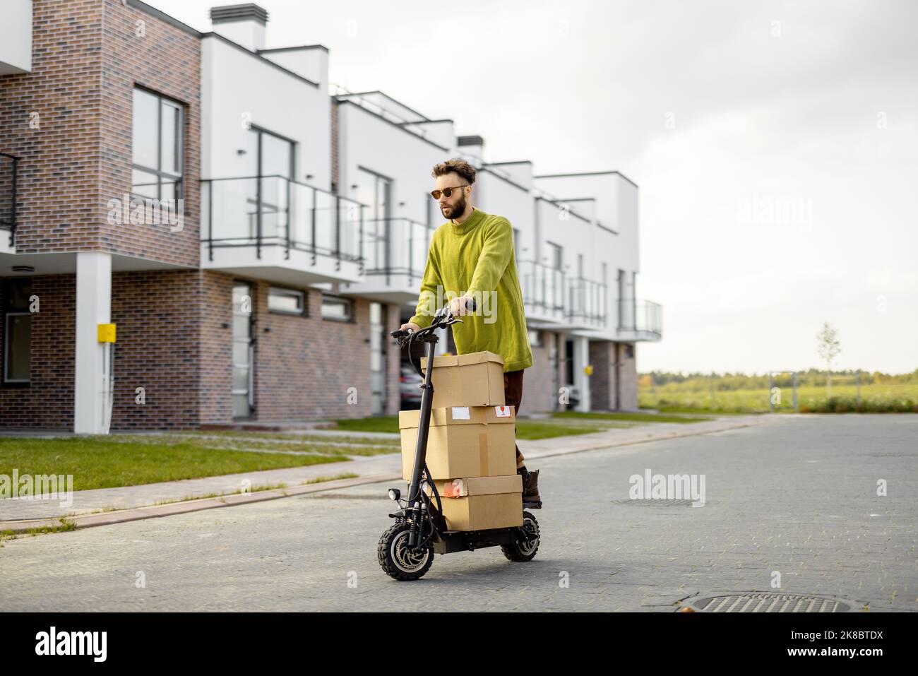 Man drives electric scooter with cardboard packages Stock Photo - Alamy
