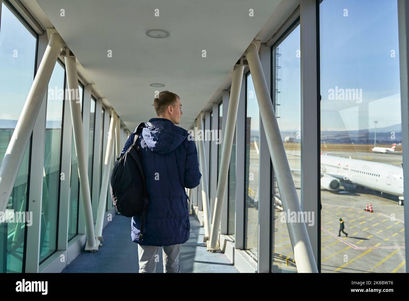 Rear view of unrecognizable male traveller walking along airport with ...