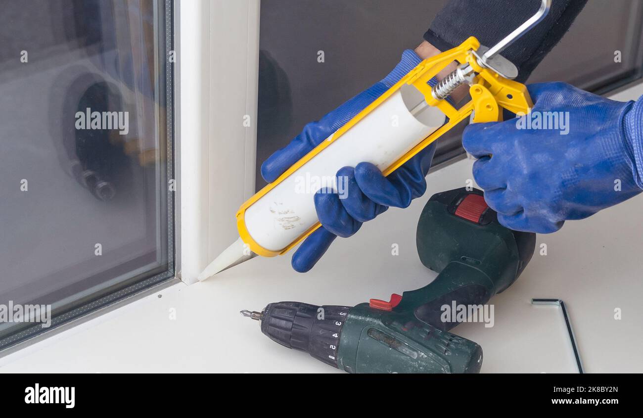 Construction worker sealing window with caulk indoors Stock Photo - Alamy
