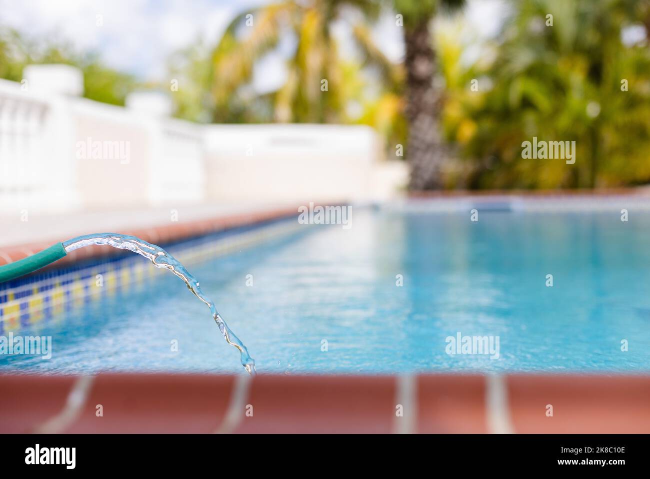 Water pipe filling up swimming pool with clean crystal water. Closeup ...