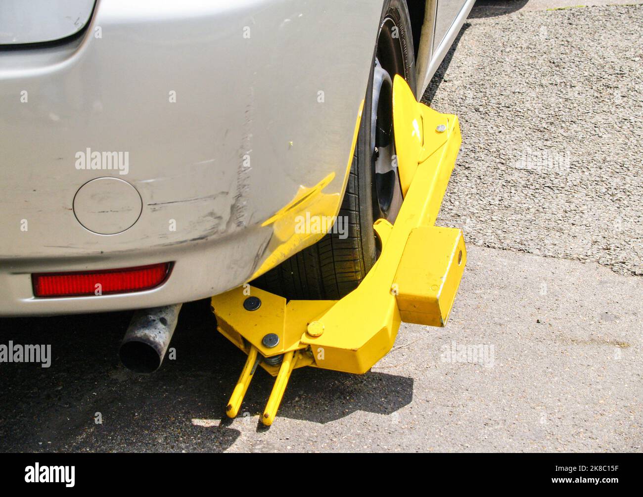 Wheel clamped with yellow clamp on city street closeup Stock Photo - Alamy