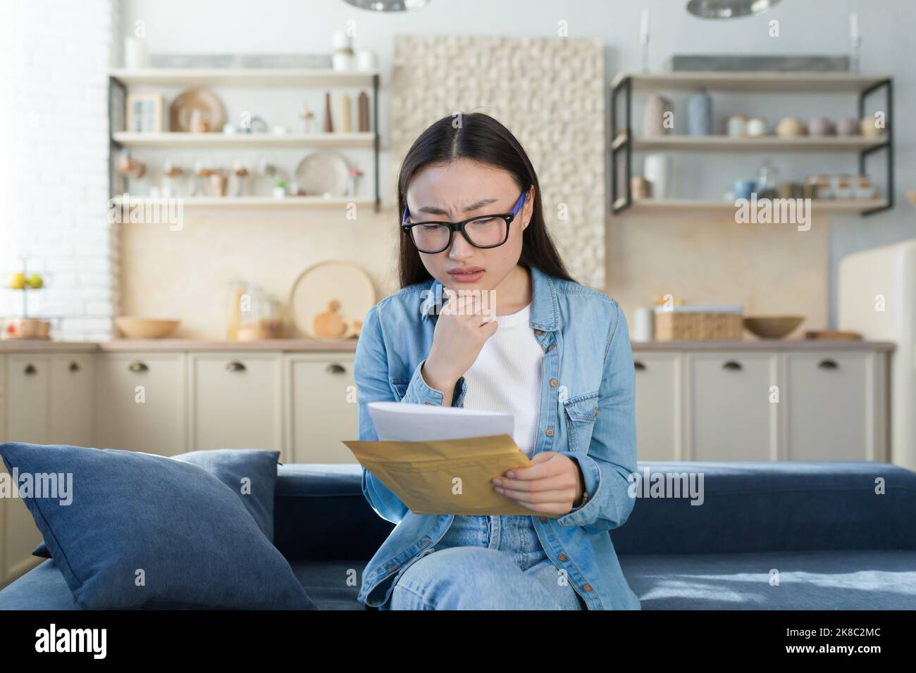 A worried young Asian woman received a letter with bills for credit ...