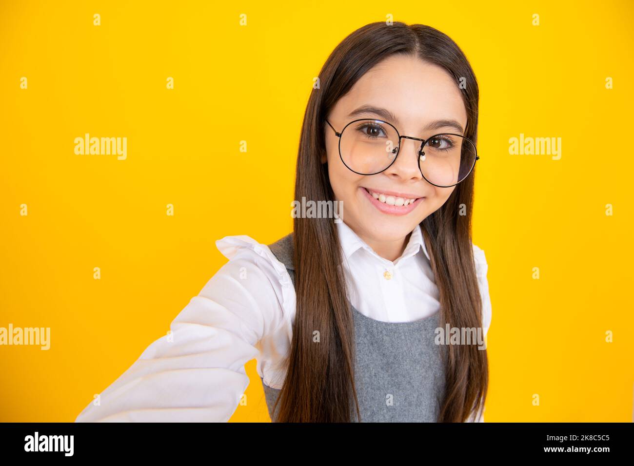 Trendy beautiful teenage model making selfie posing on yellow studio background. Teen fashion ...