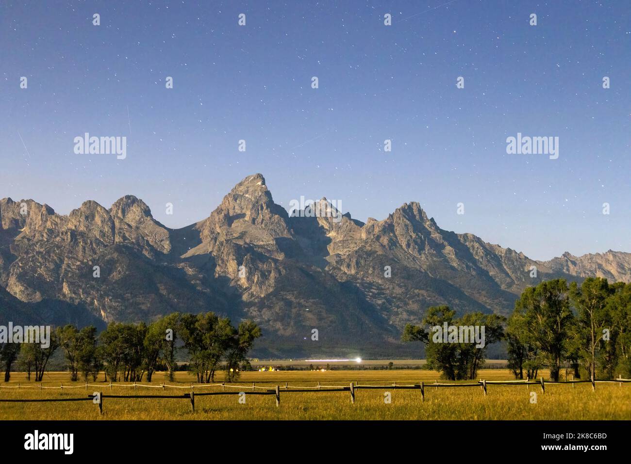 Stars glowing above the Teton Mountains as numerous headlamps shine ...