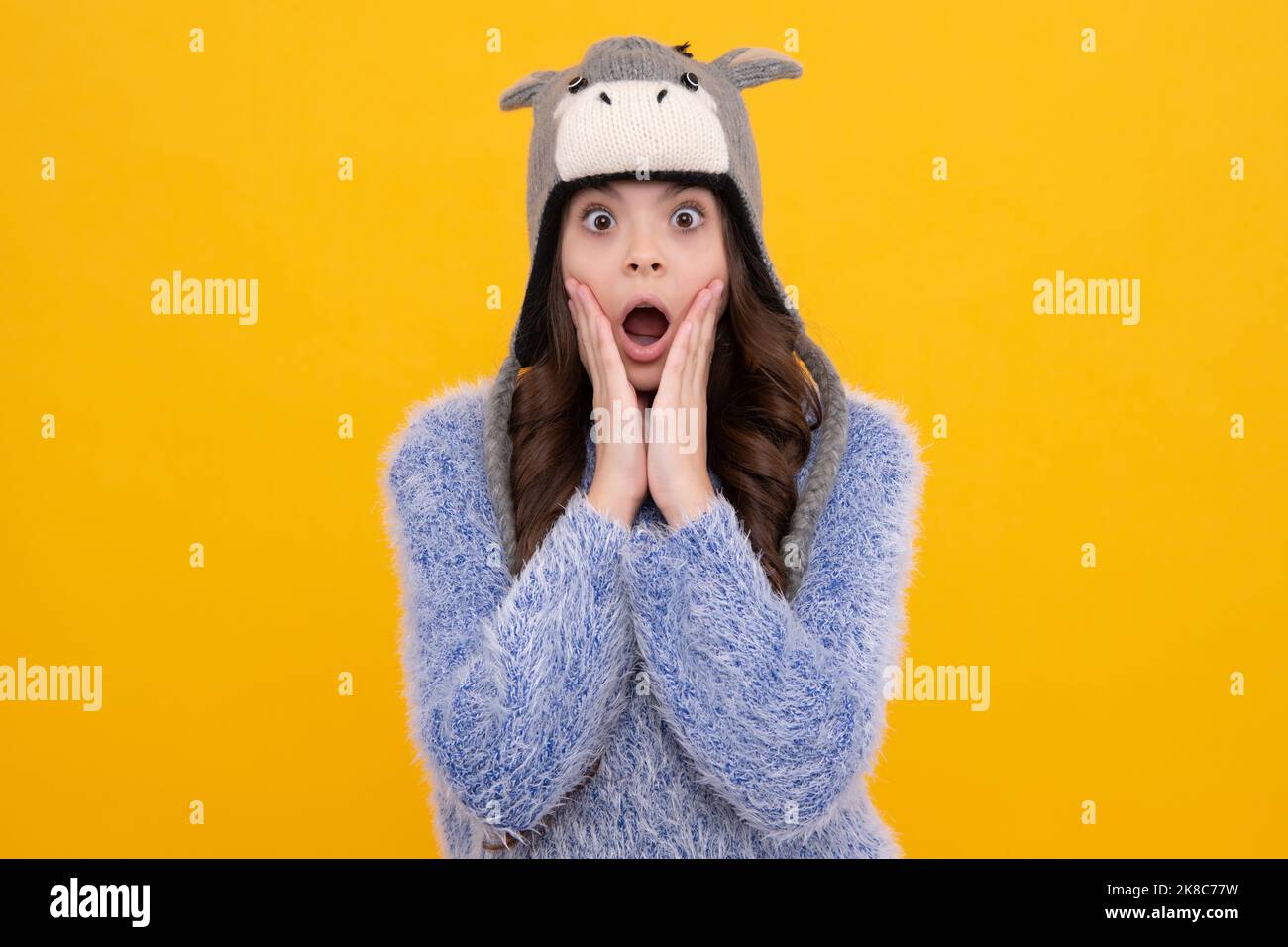 Modern teen girl wearing sweater and knitted hat on isolated yellow ...