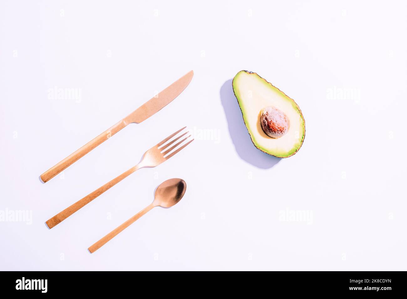 Avocado and cutlery on white background. Healthy raw vegan food concept ...
