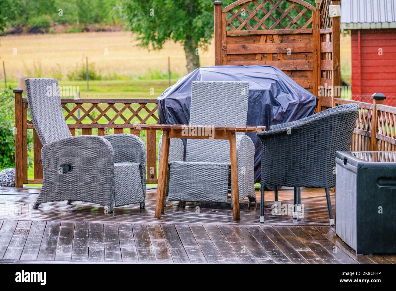 Heavy rain at wooden terrace with summer chairs, wooden table. Blurry ...