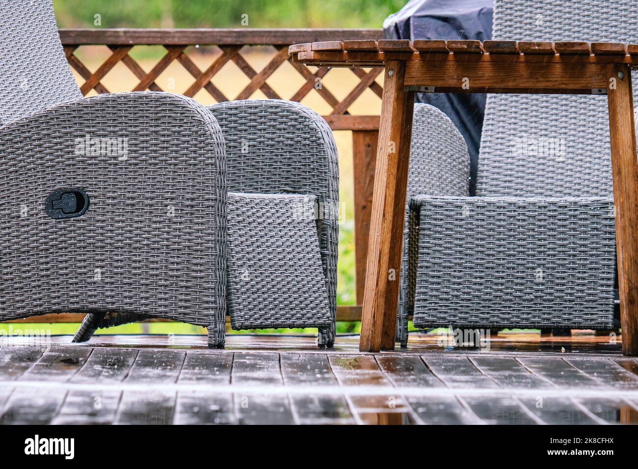 Heavy rain at wooden terrace with summer chairs, wooden table. Blurry ...