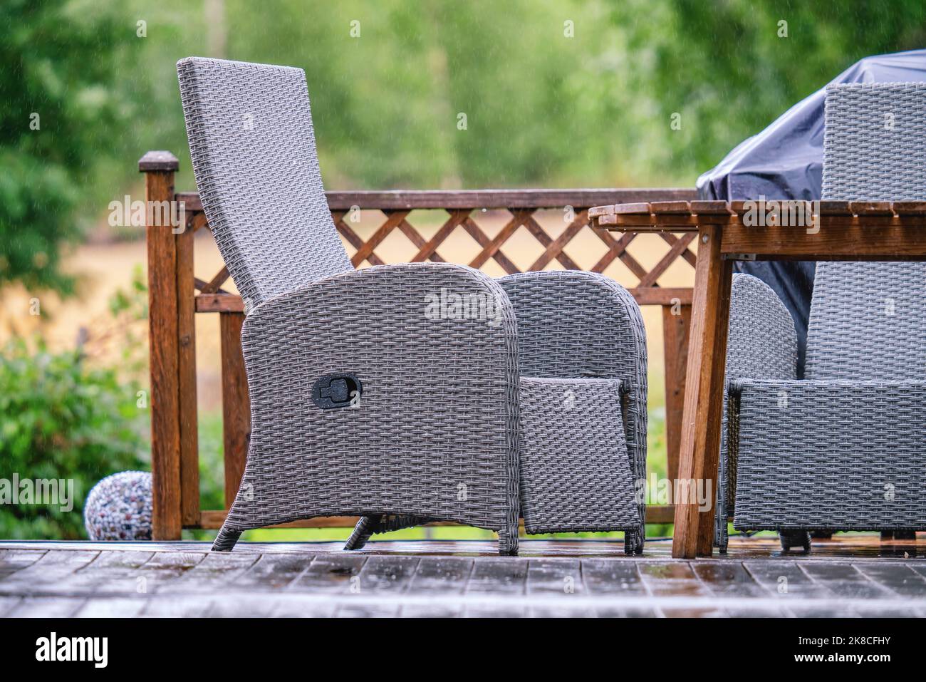 Heavy rain at wooden terrace with summer chairs, wooden table. Blurry ...