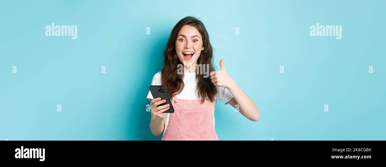 Portrait of excited cute girl say yes, smiling and nod in approval ...