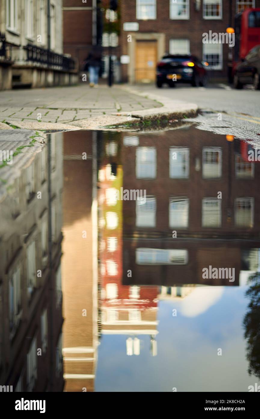 Blurred image of London street and buildings in reflection of puddle of ...