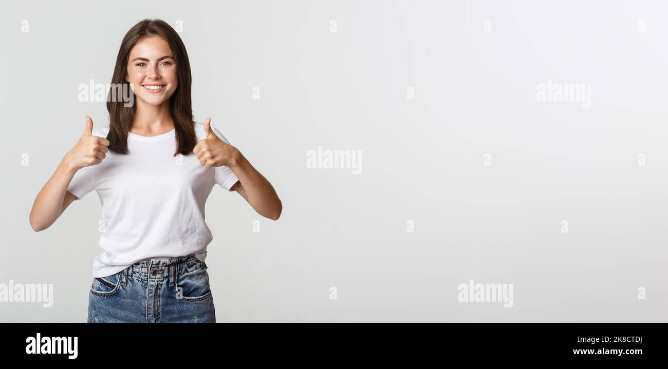 Happy satisfied young woman smiling, showing thumbs-up in approval ...