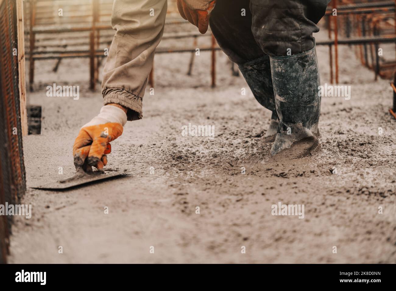 Construction site worker in boots and uniform finishing concrete on ...