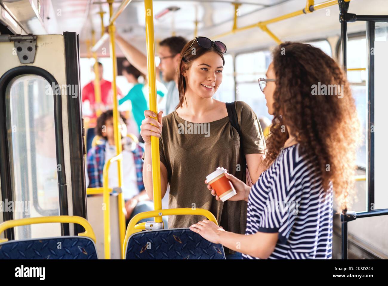Two girls in a bus standing, chatting and smiling Stock Photo - Alamy
